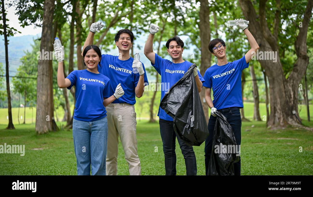 A group of cheerful young Asian volunteers is standing in a public park ...