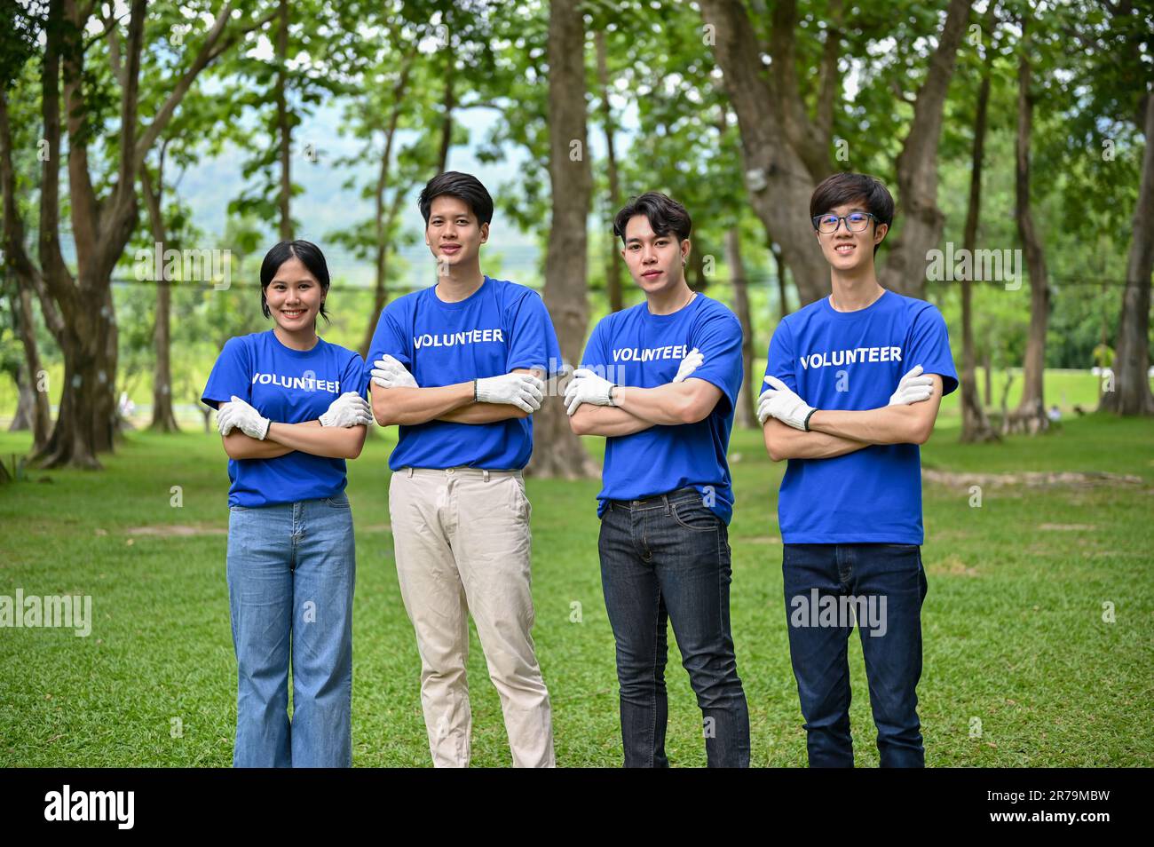 A group of happy young Asian volunteers in uniform standing in the ...