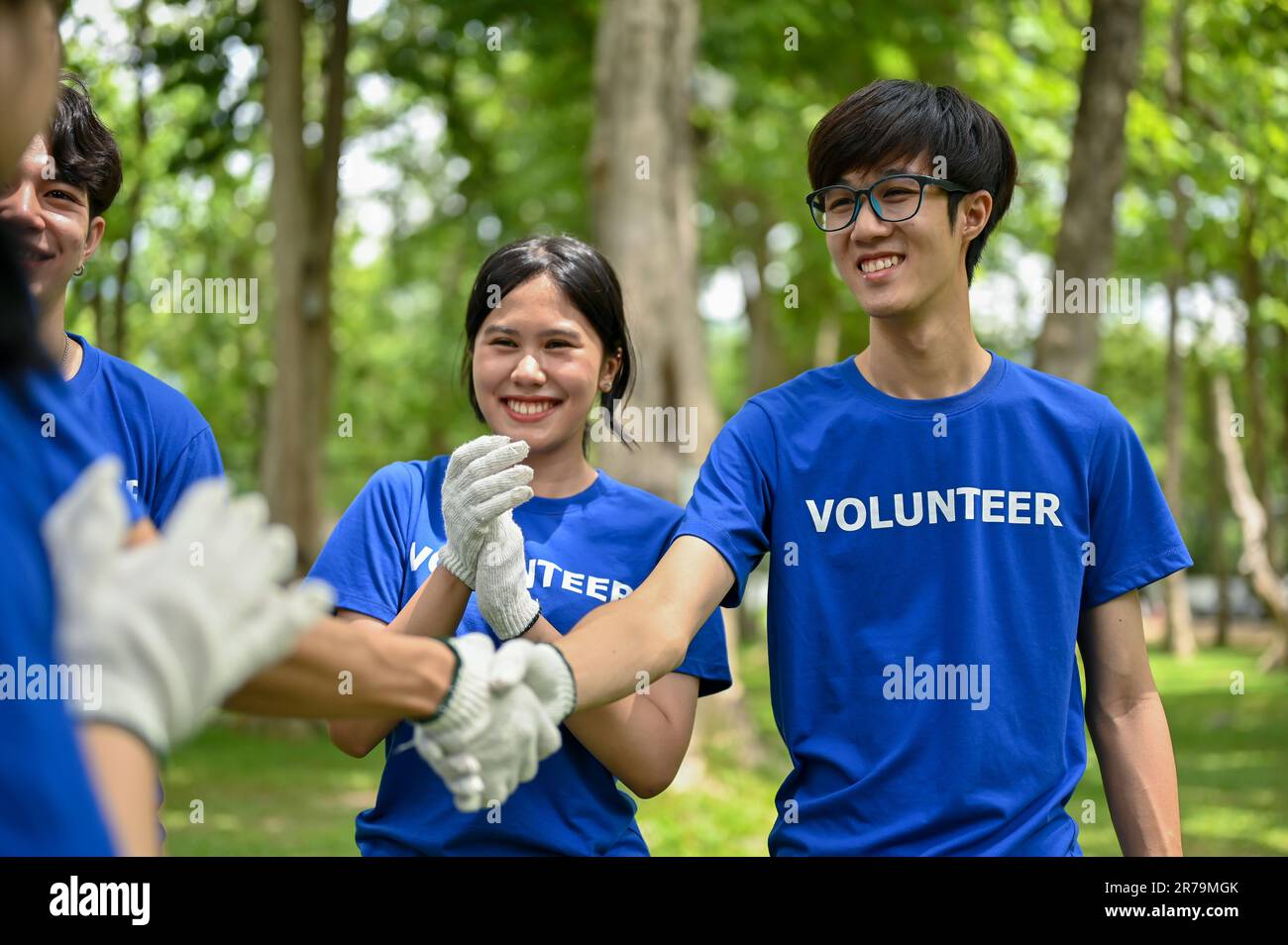 A happy young Asian male volunteer shakes hands with his team after ...