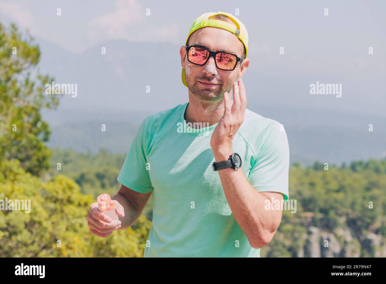 Hiker sporty man sky runner applying sun cream to protect skin from ...