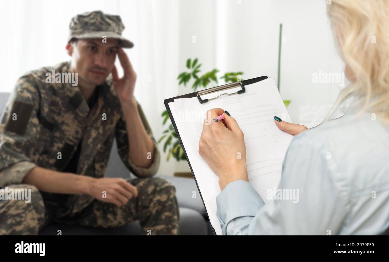 Psychologist making notes during therapy session with sad male soldier ...