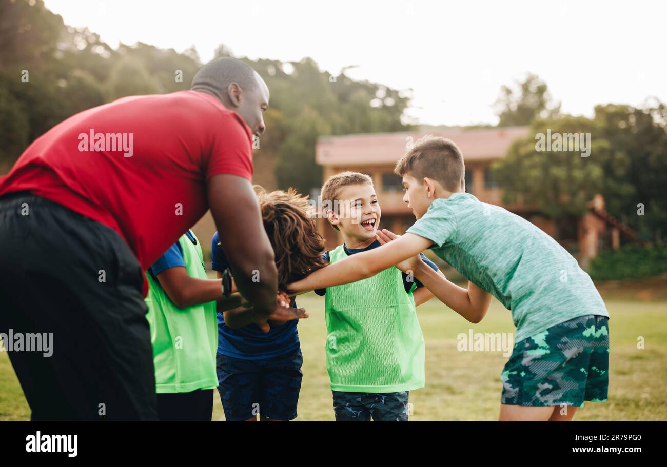 school sports team having a huddle in a rugby field. Trainer giving his ...