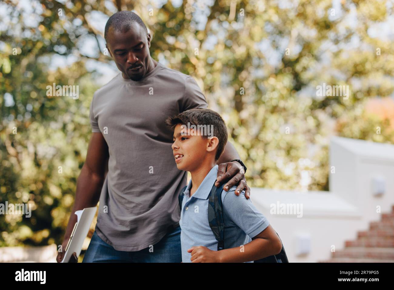 Male teacher walking outdoors with a young student. Educator taking a ...