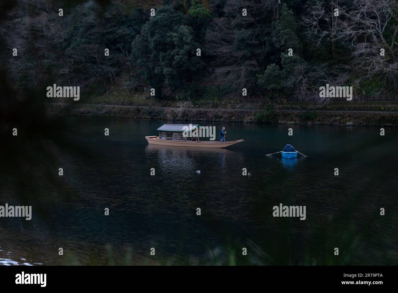 A group of people in a small boat leisurely paddling on a tranquil body ...