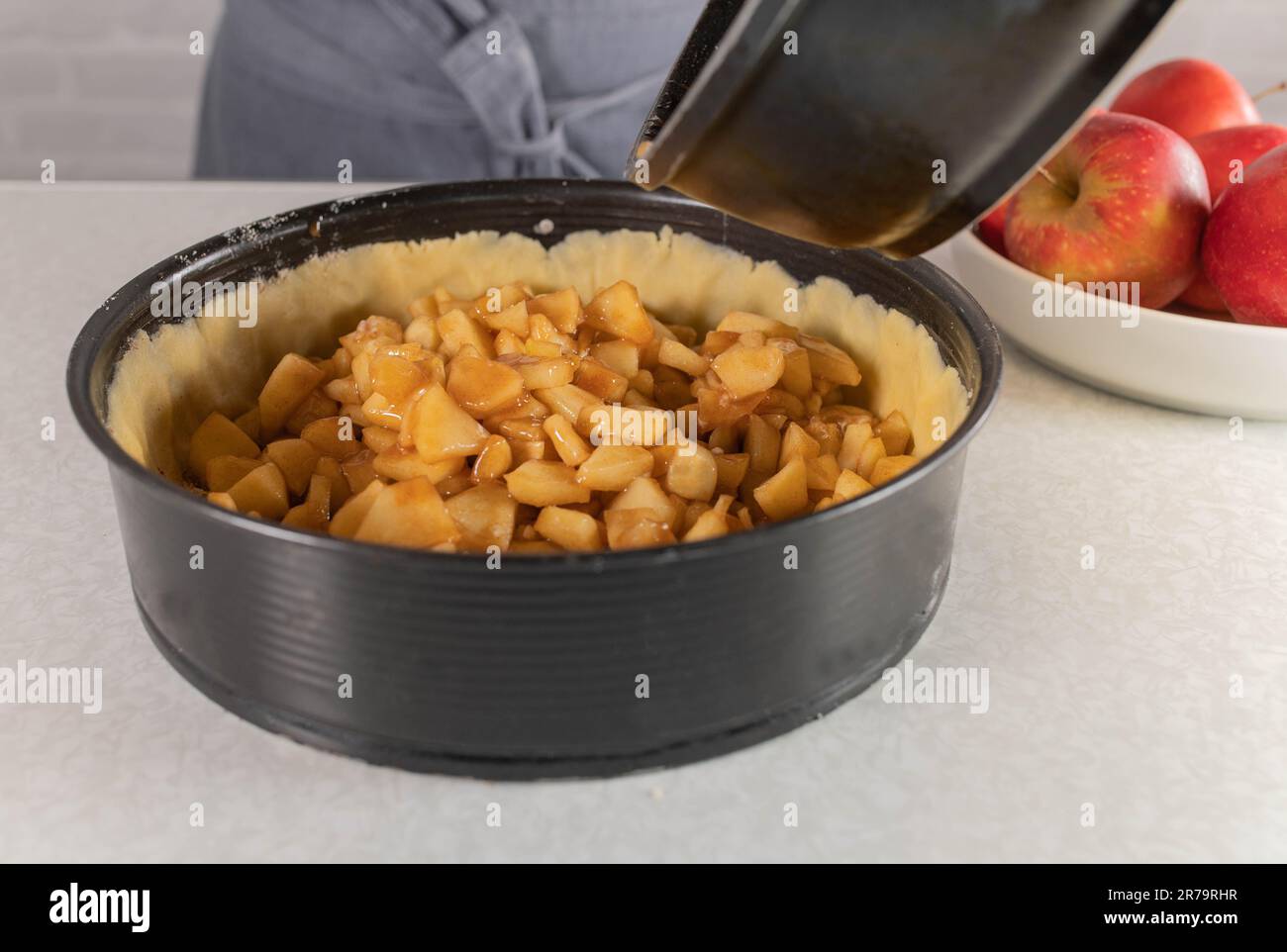 Making apple pie with short crust pastry in a round baking pan. Part of ...