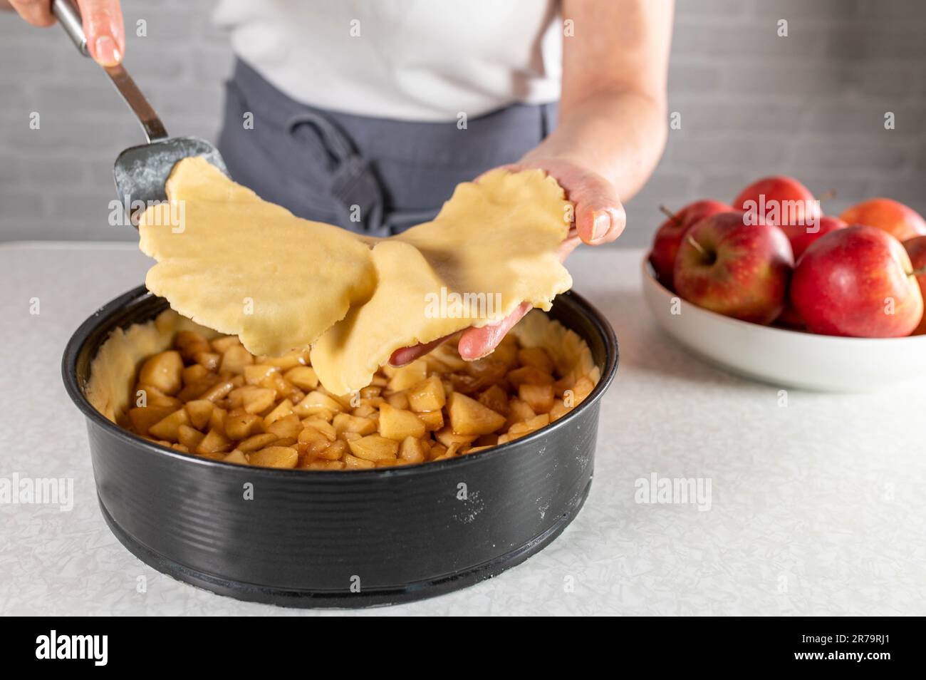 Making apple pie with short crust pastry in a round baking pan. Part of ...