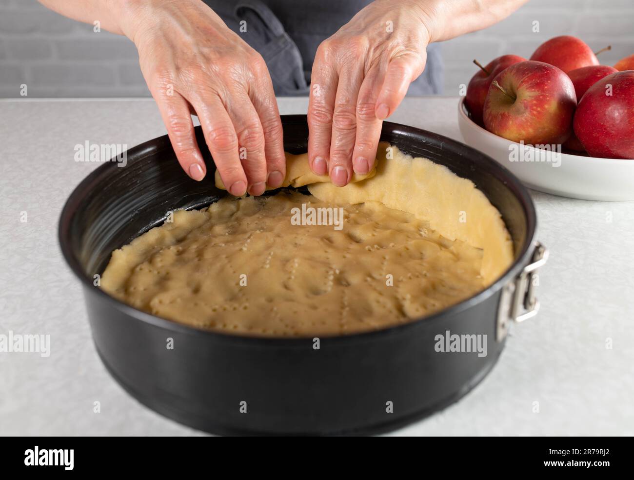 Making apple pie with short crust pastry in a round baking pan. Part of ...