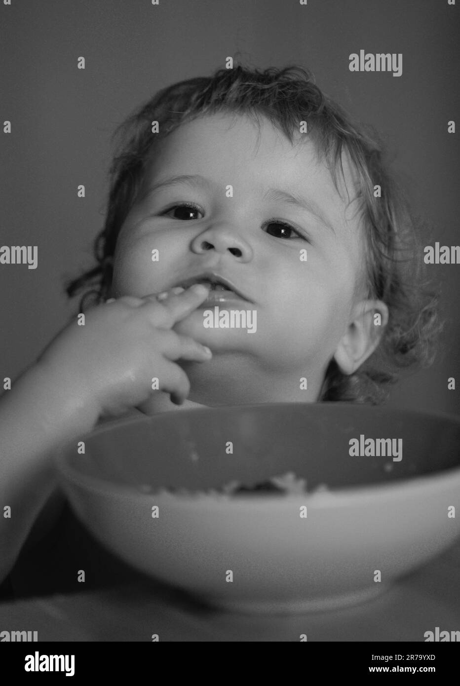 Happy baby eating himself with a spoon. Healthy nutrition for kids ...