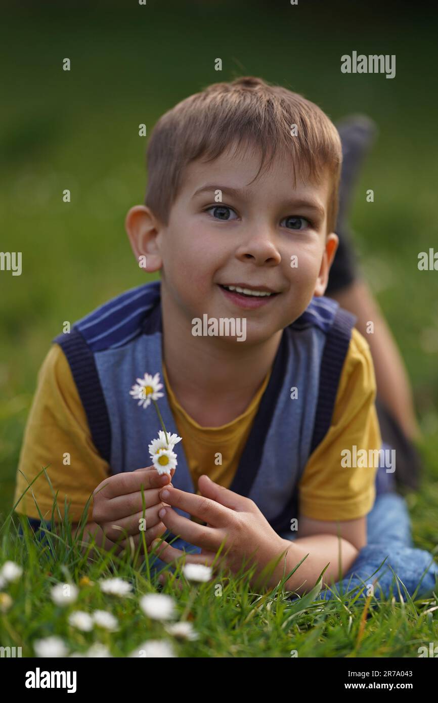 Happy child lying in a summer meadow, portrait. Hello summer Stock ...