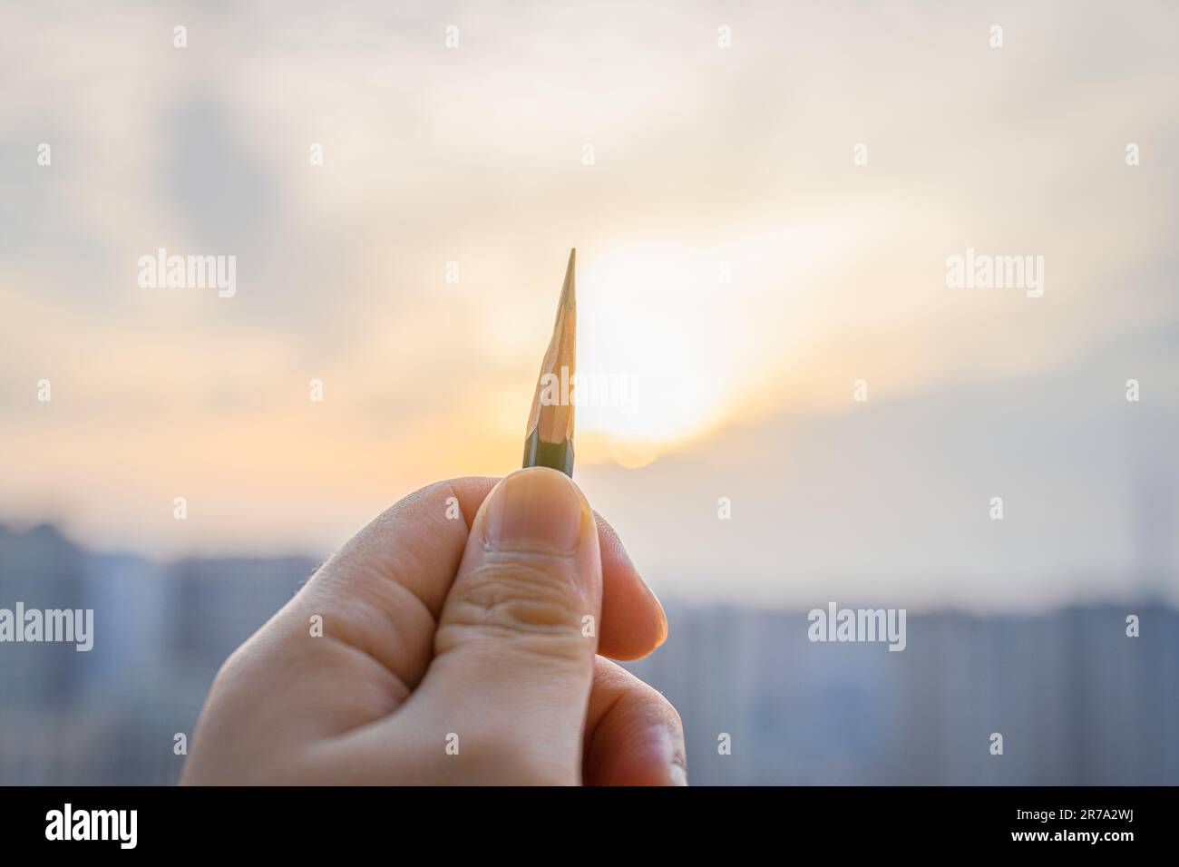 A hand holding a pencil under the sunlight Stock Photo - Alamy