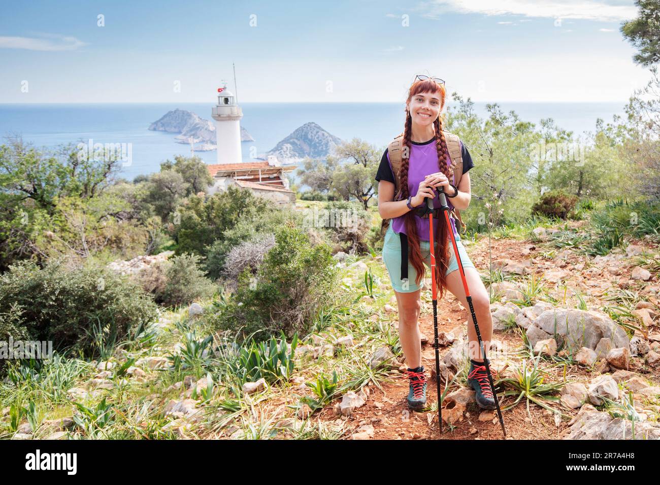 Happy redhead hiker girl with trekking poles and backpack walking by ...