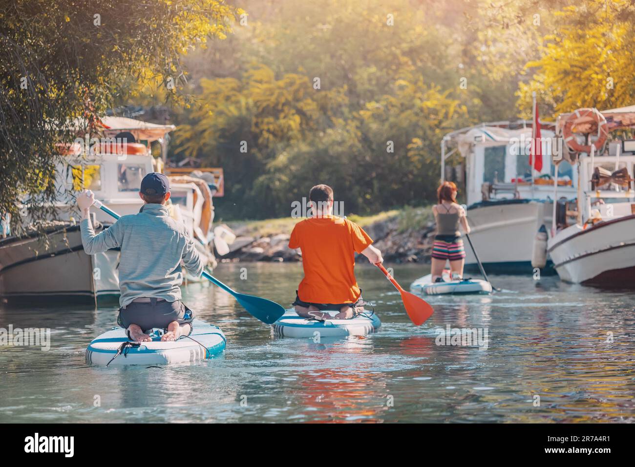 Group of people on a sup boards swimming by a narrow channel among ...