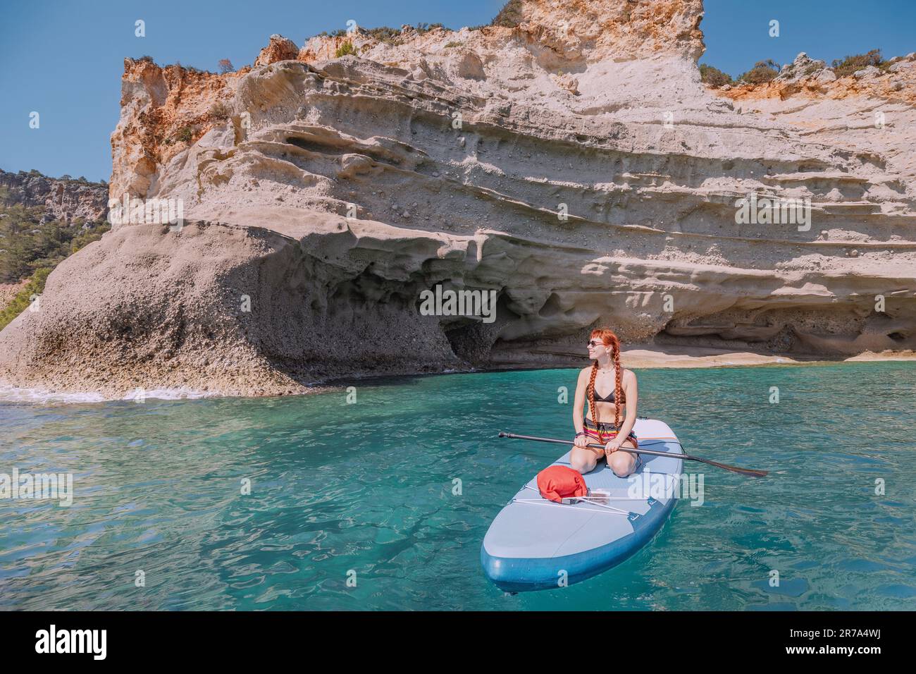 Happy Girl In A Swimsuit With A Paddle Swims On A Sup Board On The Sea