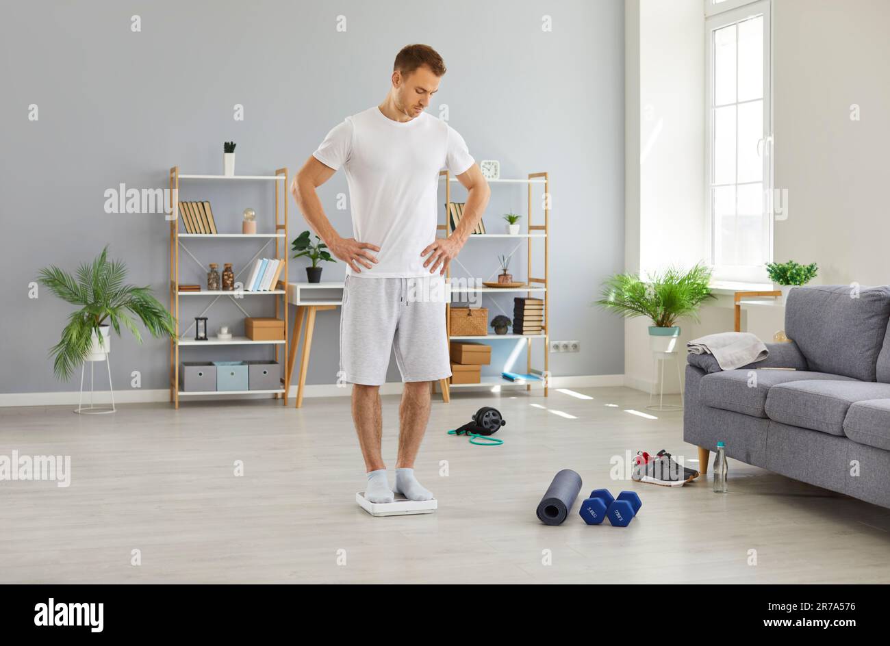 Fit man weighing himself on scales and looking how much weight he has ...