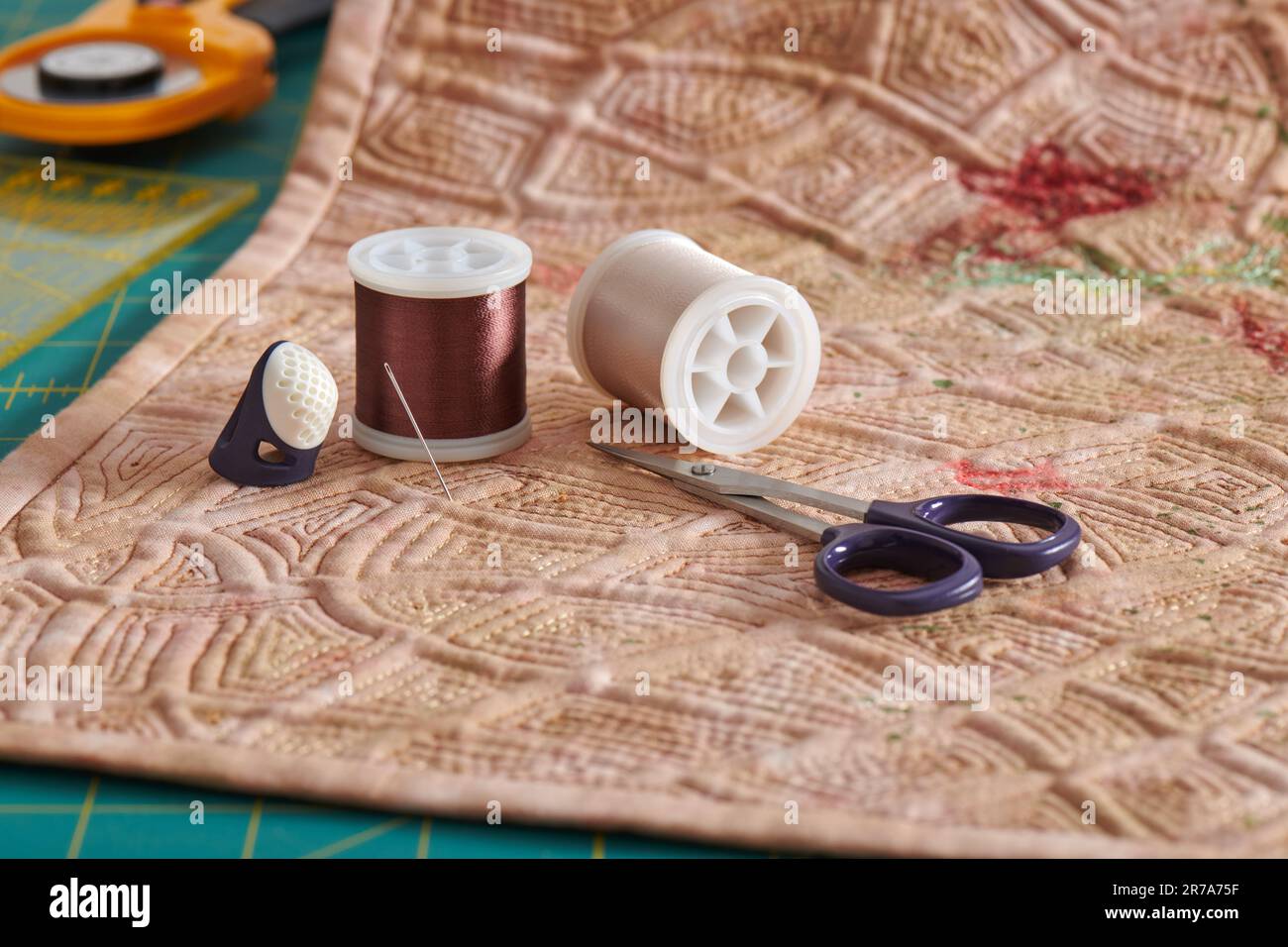 Sewing accessories lying on a reverse side of a quilt, cutting mat ...