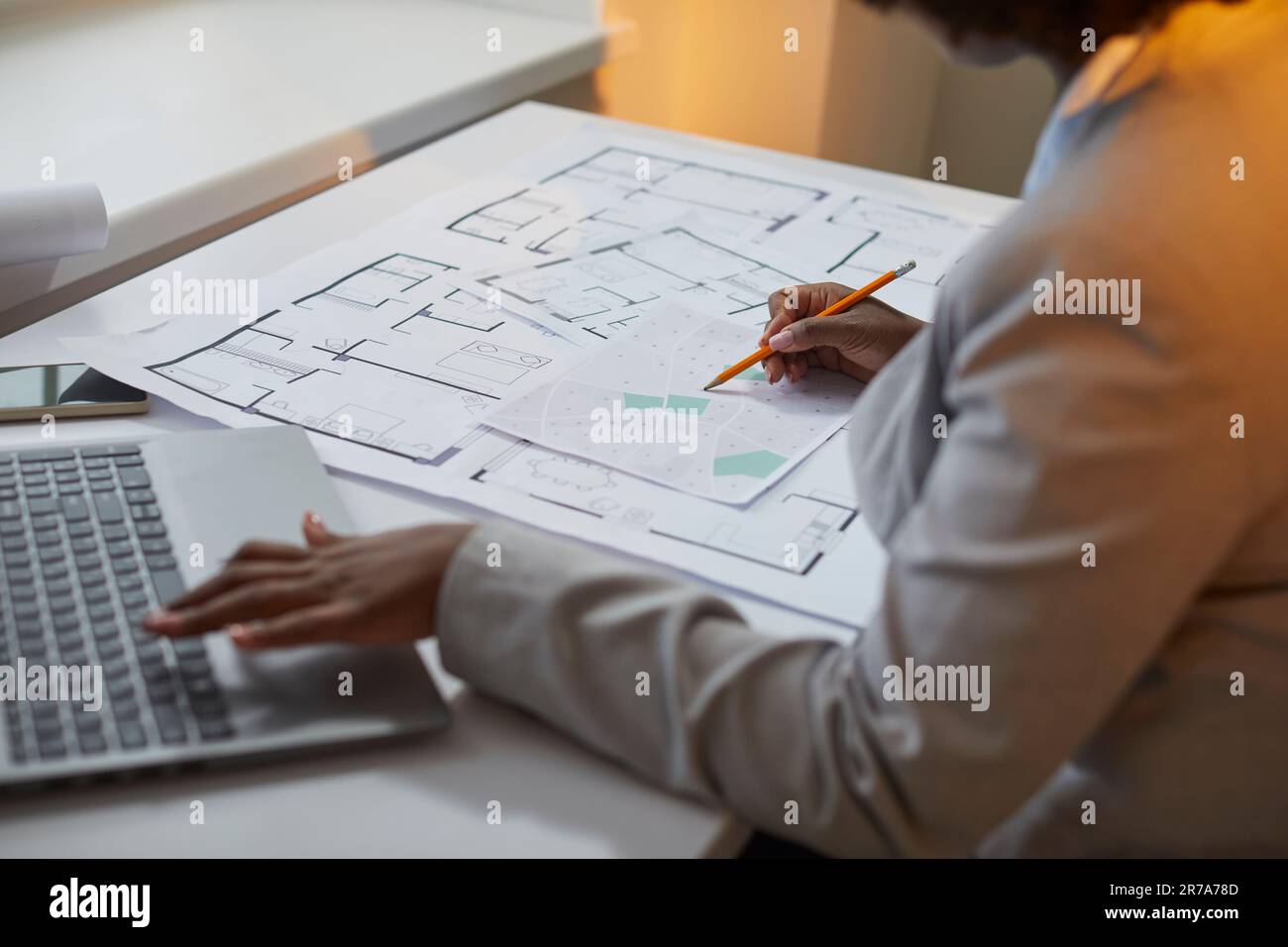 Woman architect using her laptop while working with blueprints, city ...