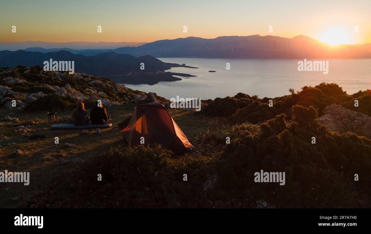 Two people are enjoying a beautiful sunset while relaxing at a campsite ...
