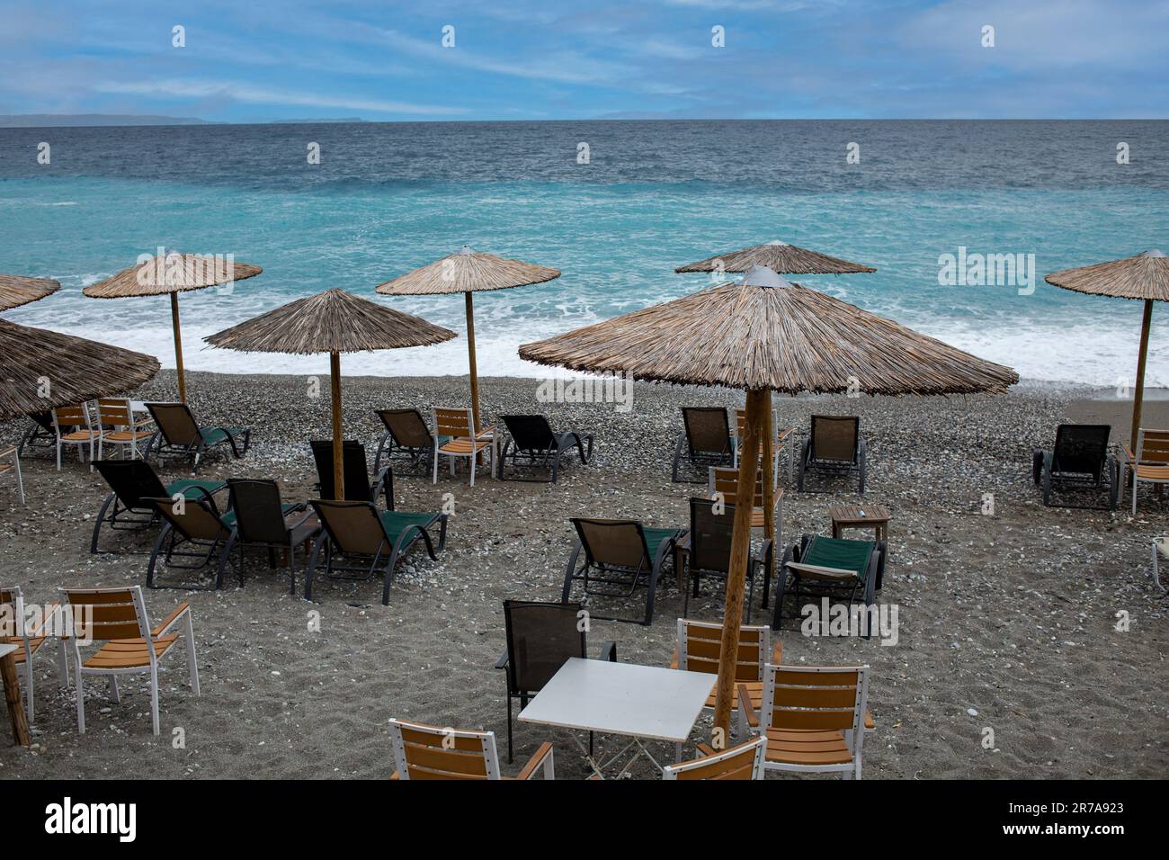Tranquil beach resort scene with parasols, lounge chairs and thatched ...