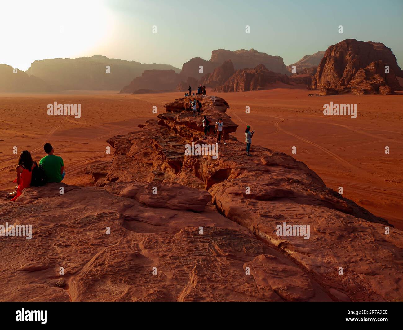 A group of people stand in awe of the peaceful sunset at Wadi Rum, a ...