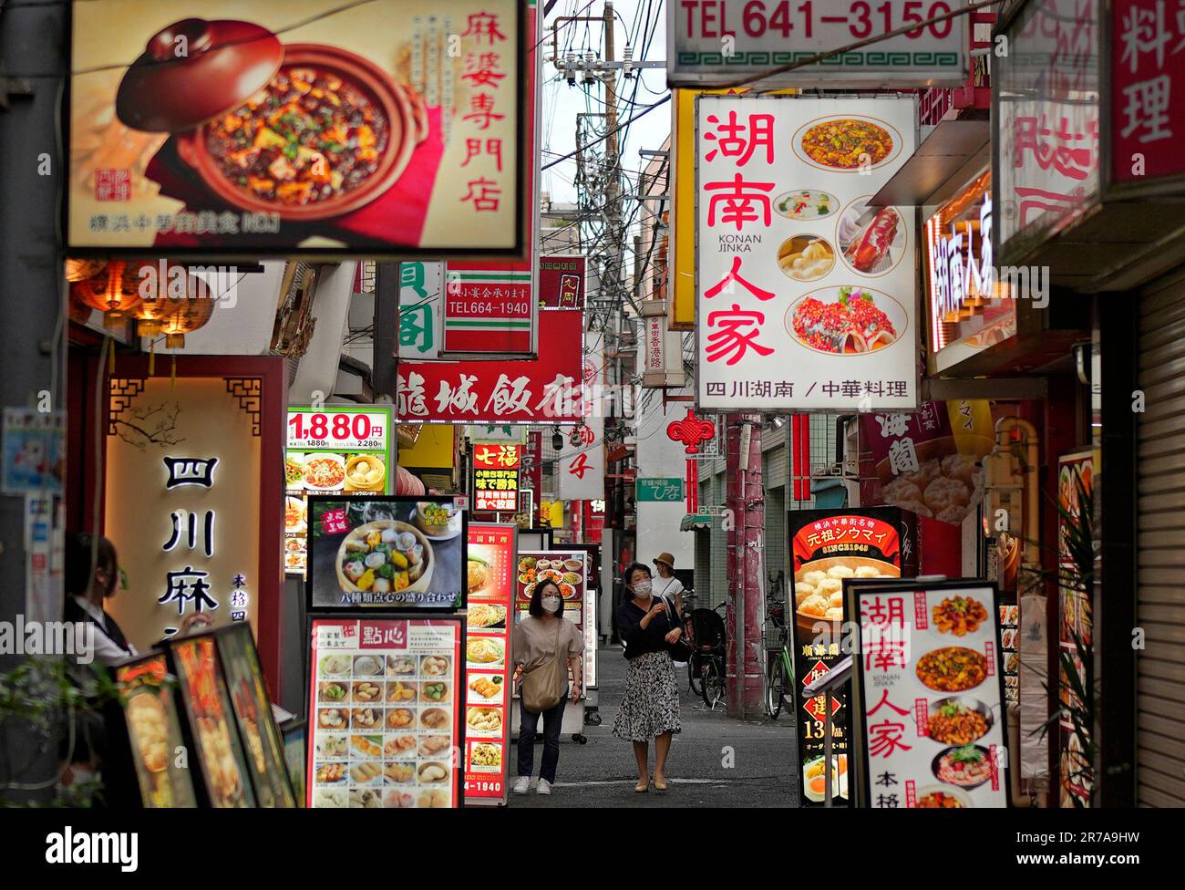 People walk through restaurants' signs at China Town in Yokohama, south ...