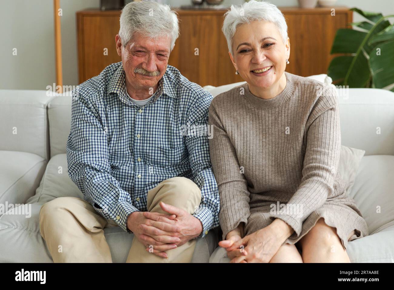 Senior Adult Mature Couple In Love Looking At Camera Sitting On Couch