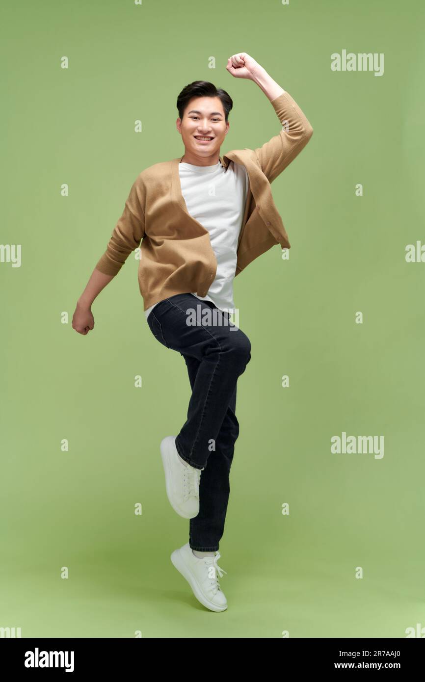 Happy energetic young Asian man jumping yelling and clenching fists ...
