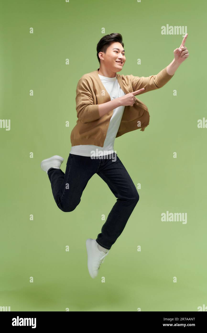 Full length excited young man jump high point index finger aside on ...