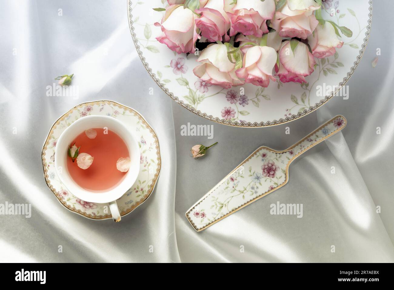 A delicate white porcelain teacup filled with fragrant rose buds sits ...