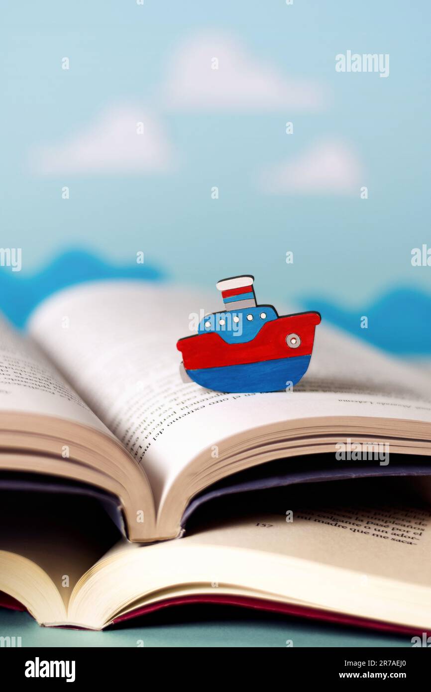 A white open book with a boat-shaped magnet resting on the cover Stock ...