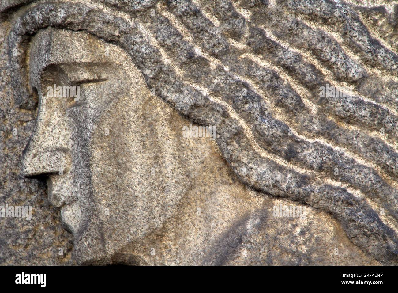 A close-up image of a face carved into a stone relief, with detailed ...