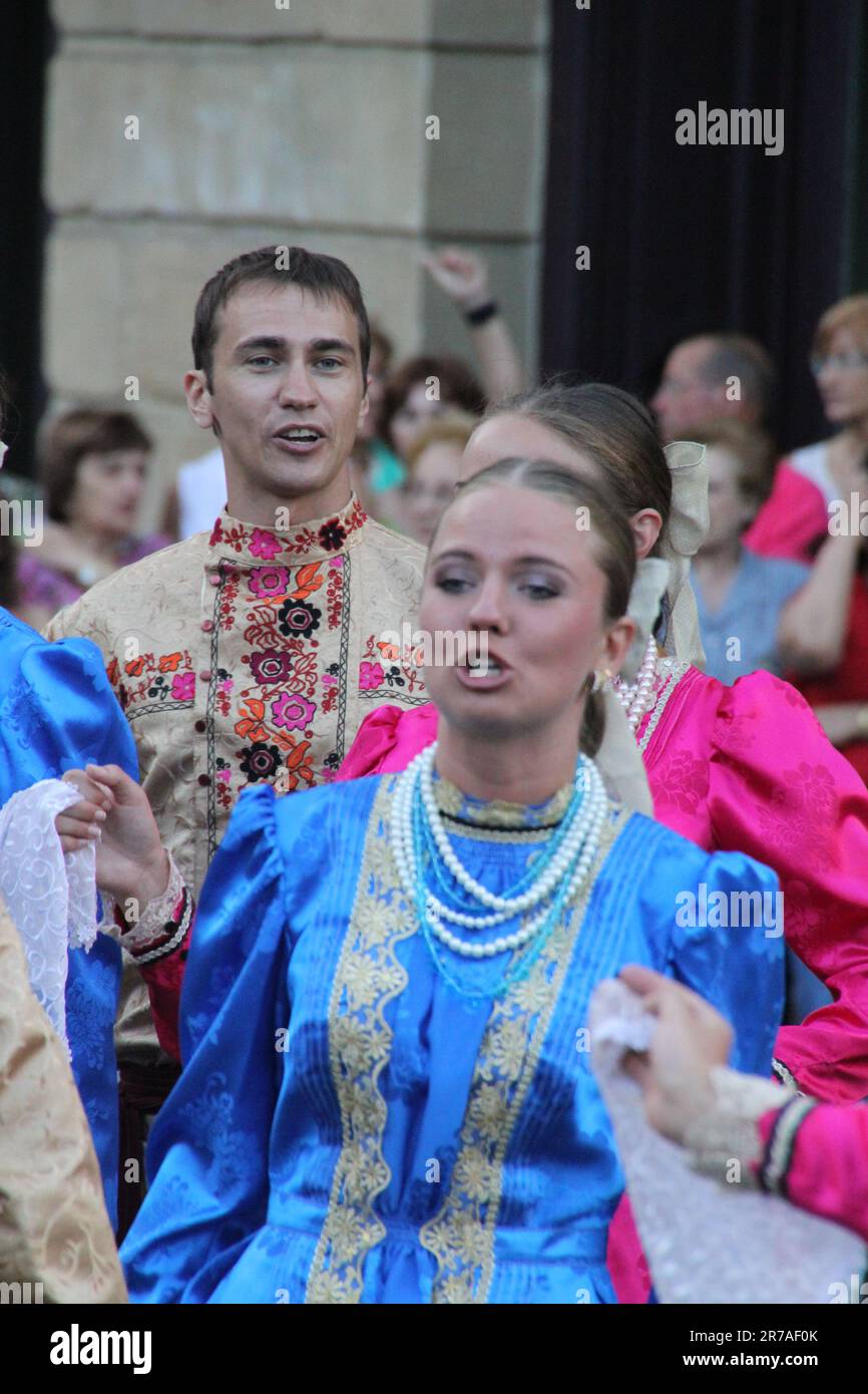 Three people of different genders wearing colorful clothing stand in a ...