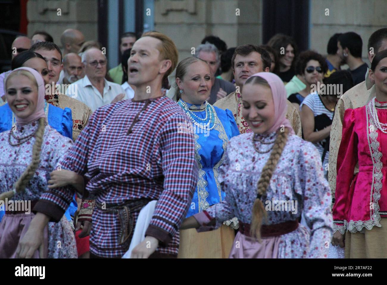 A cheerful group of people wearing traditional folk costumes joyfully ...