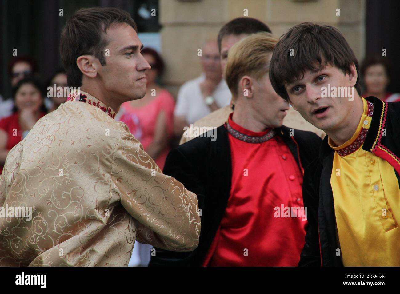 Three young men wearing vibrant clothing standing side by side in an ...