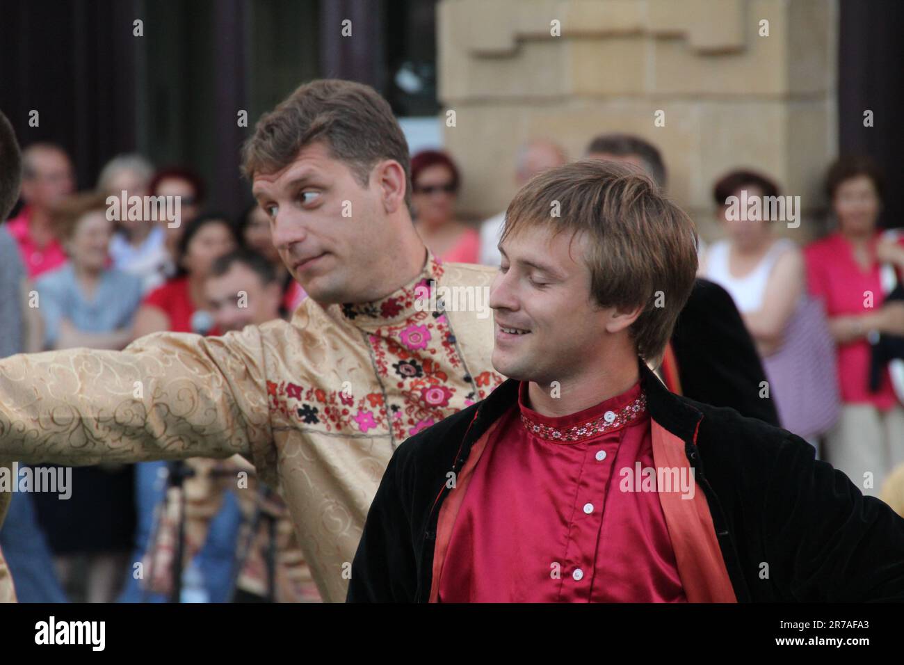 Two male adults wearing traditional costumes are dancing in an ...