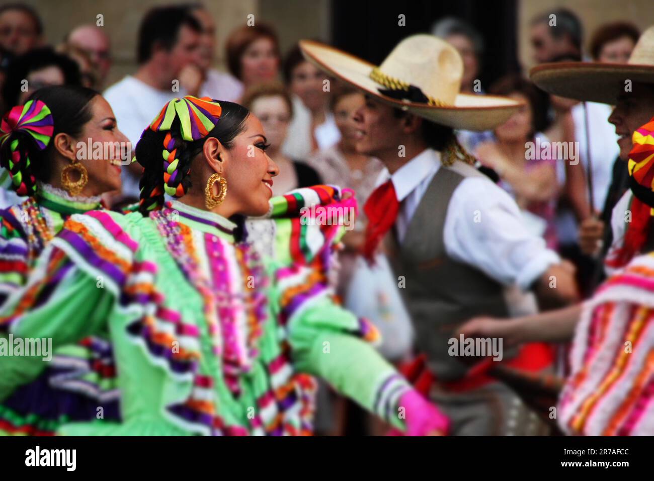 Three dancers in colorful, ornate costumes captivate a lively audience ...