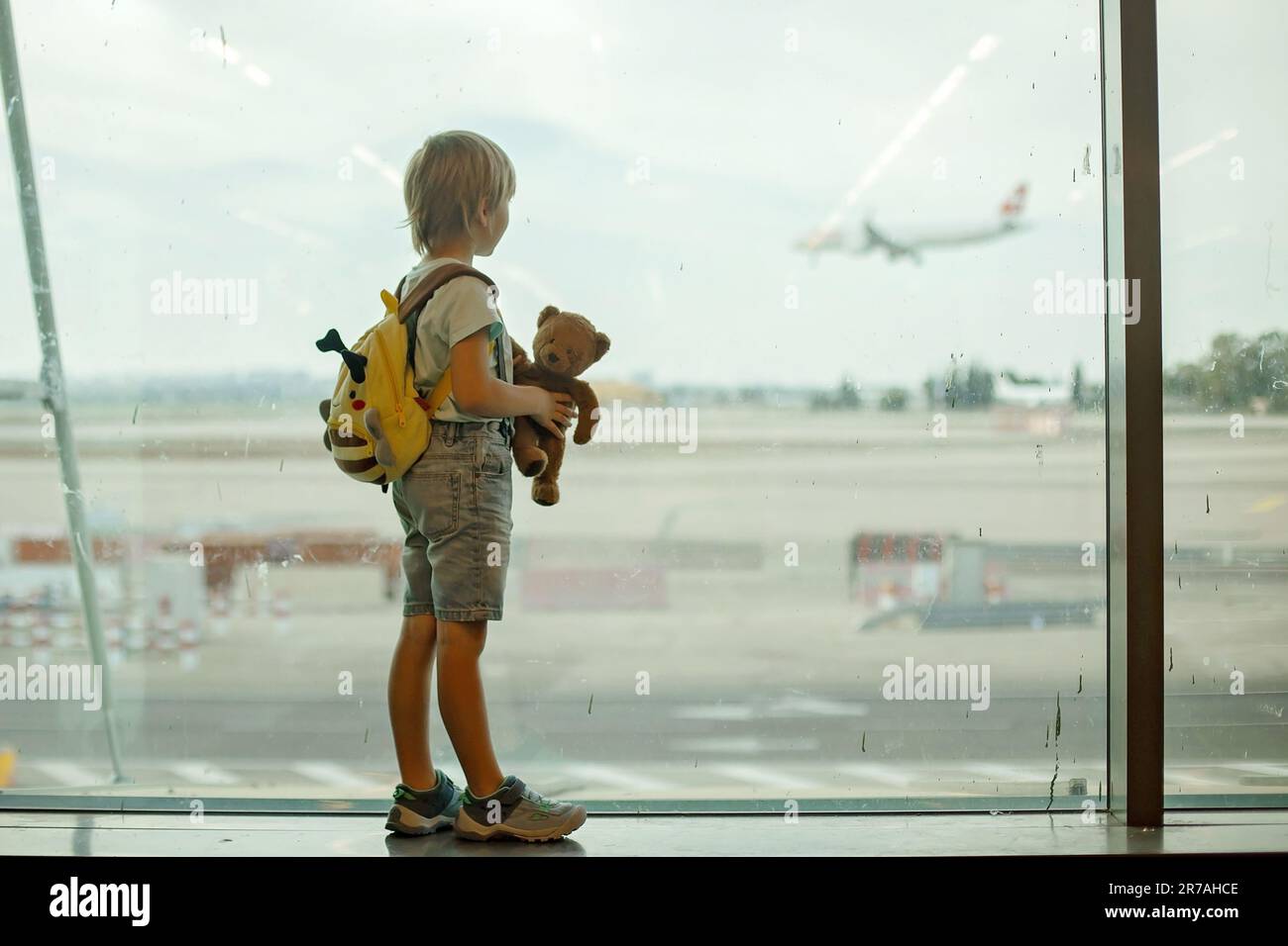 Child, watching from the window of the airport the planes, taking off ...