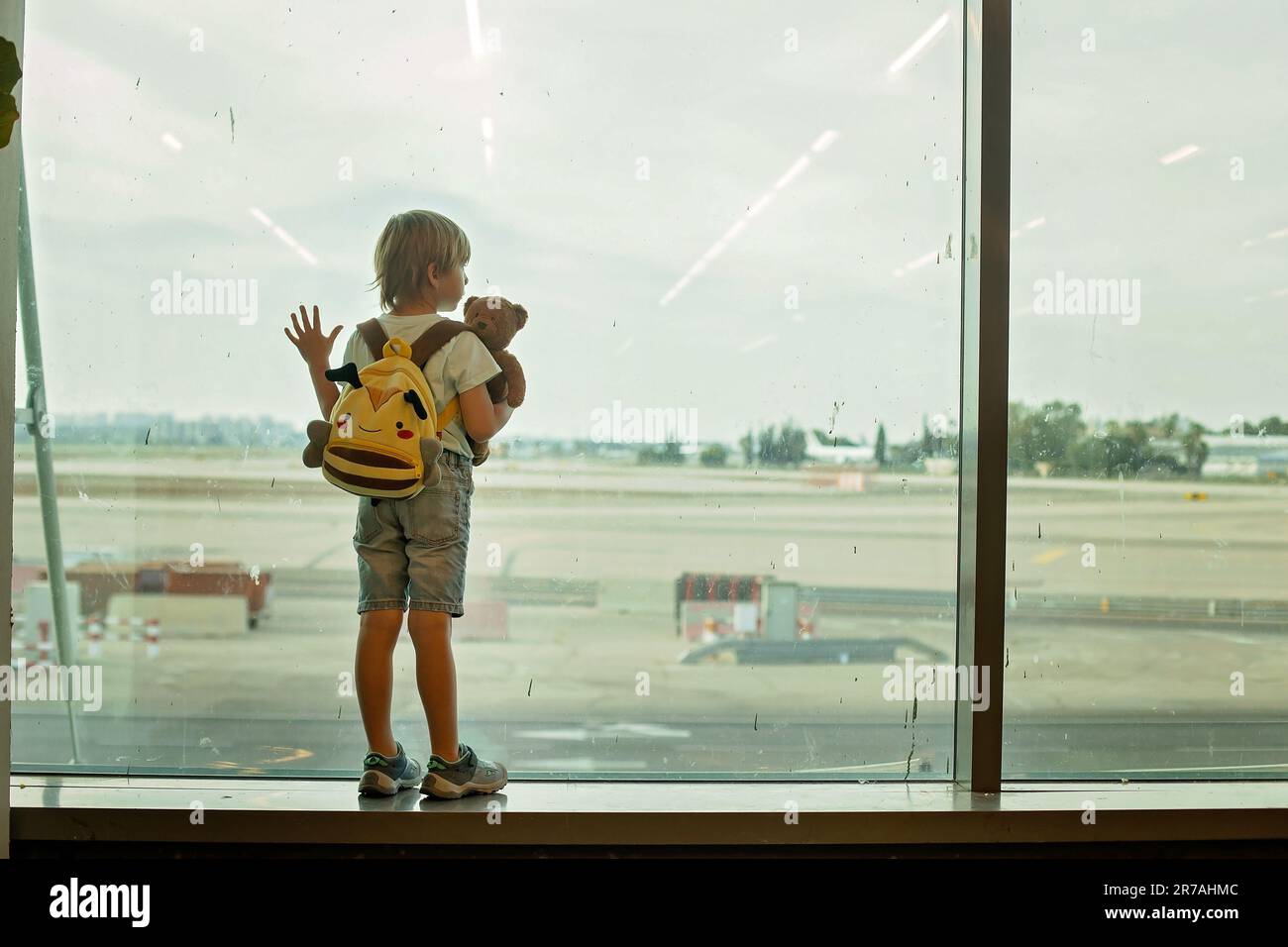 Child, watching from the window of the airport the planes, taking off ...