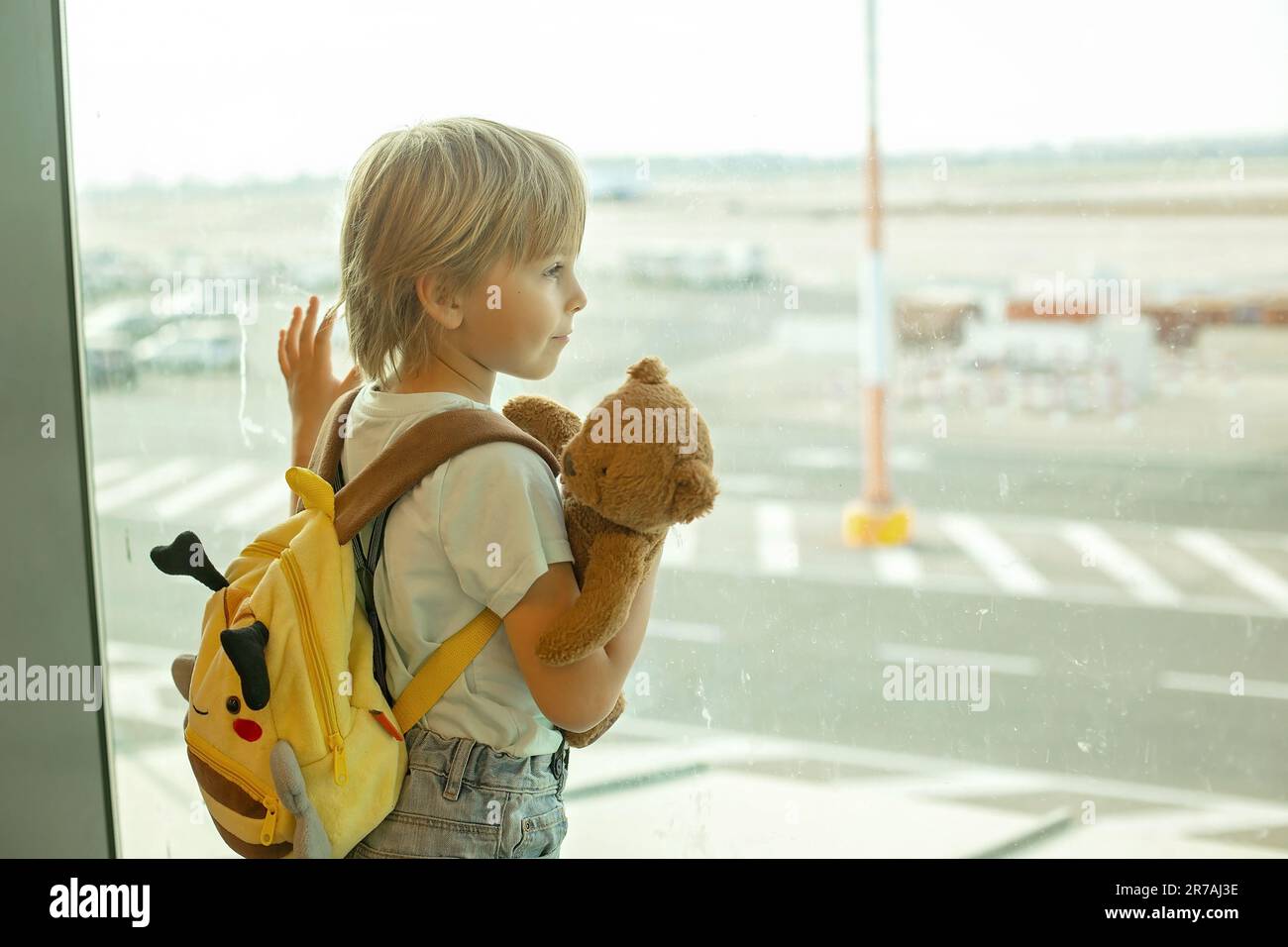 Child, watching from the window of the airport the planes, taking off ...