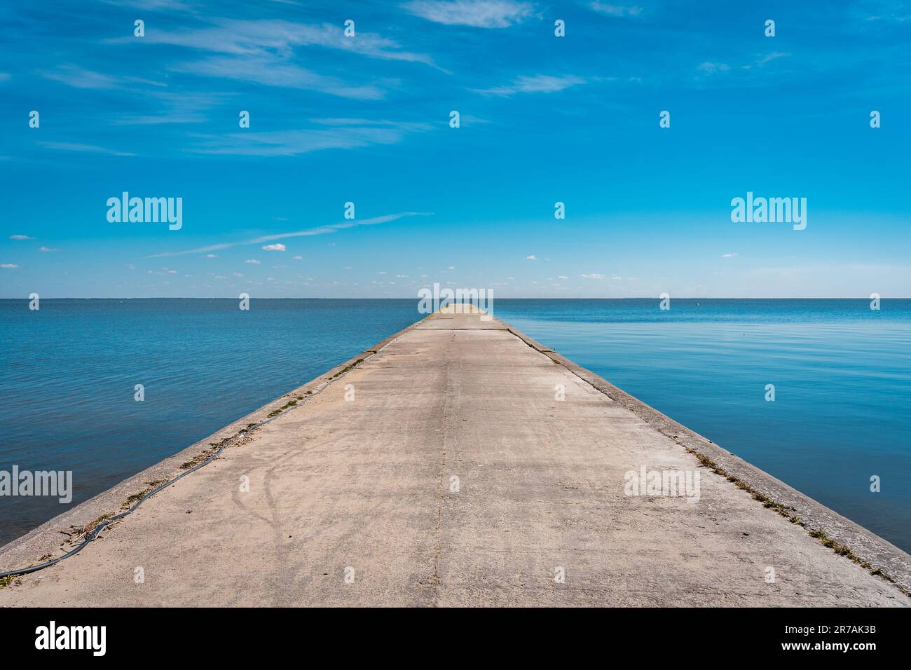 A long stone pier goes far into the sea against the background of a ...