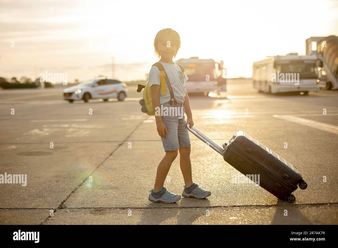 Cute blond child, kid with backpack, boarding airplane at the airport ...
