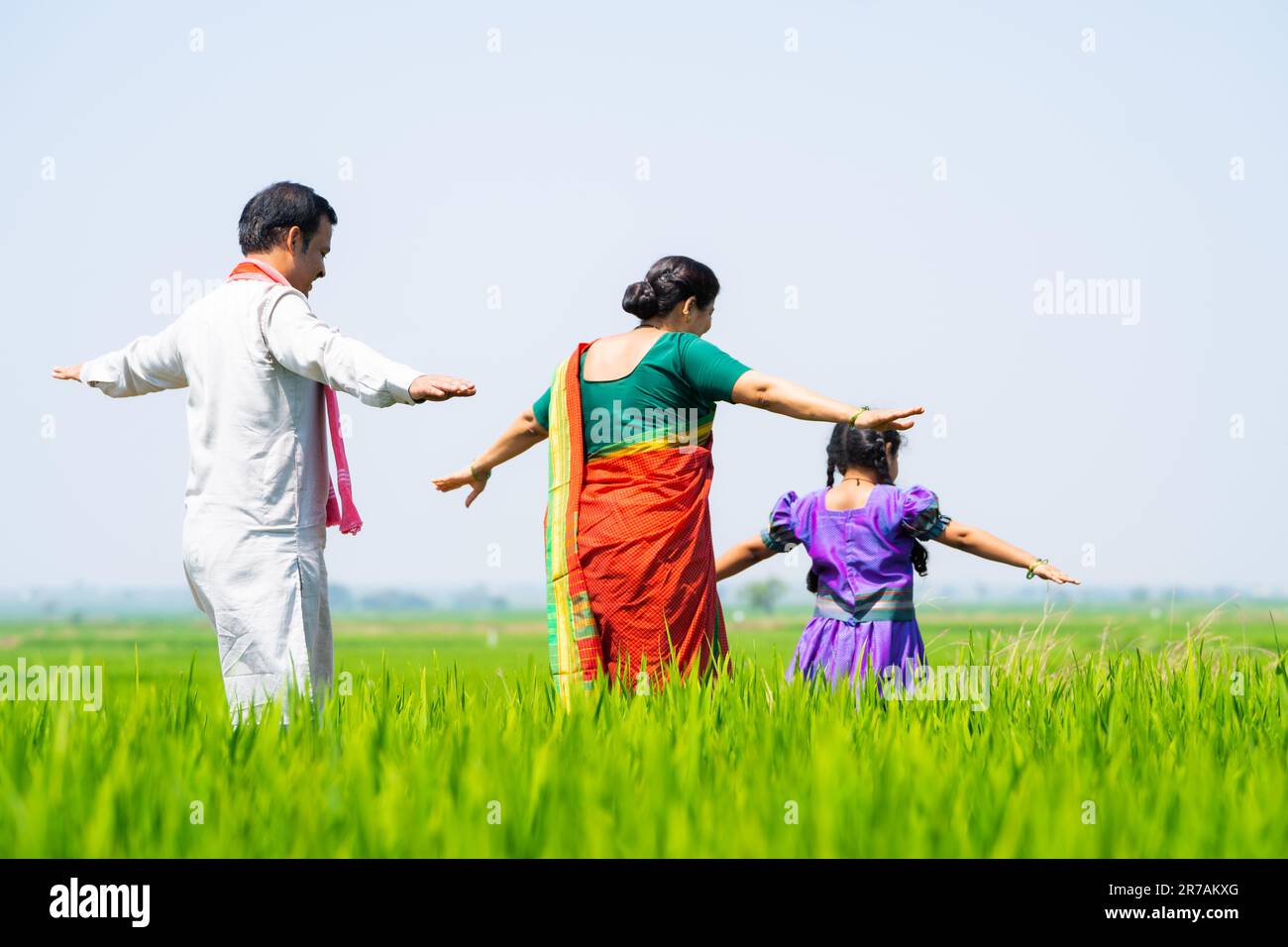 rear view wide shot of joyful village farming couple with kid walking ...