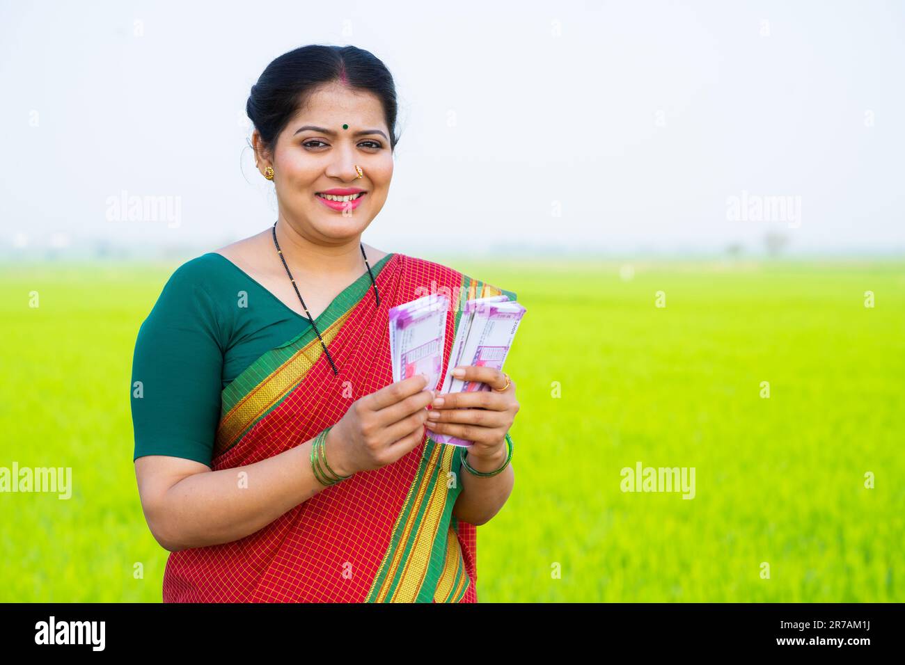 Happy smiling indian village woman showing money at green paddy ...