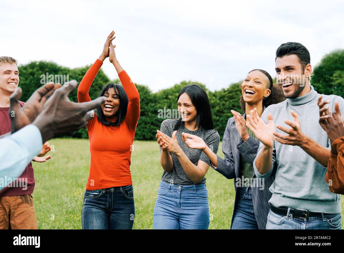 Happy group of people celebrating, clapping hands outdoors - Multiracial friends having fun ...