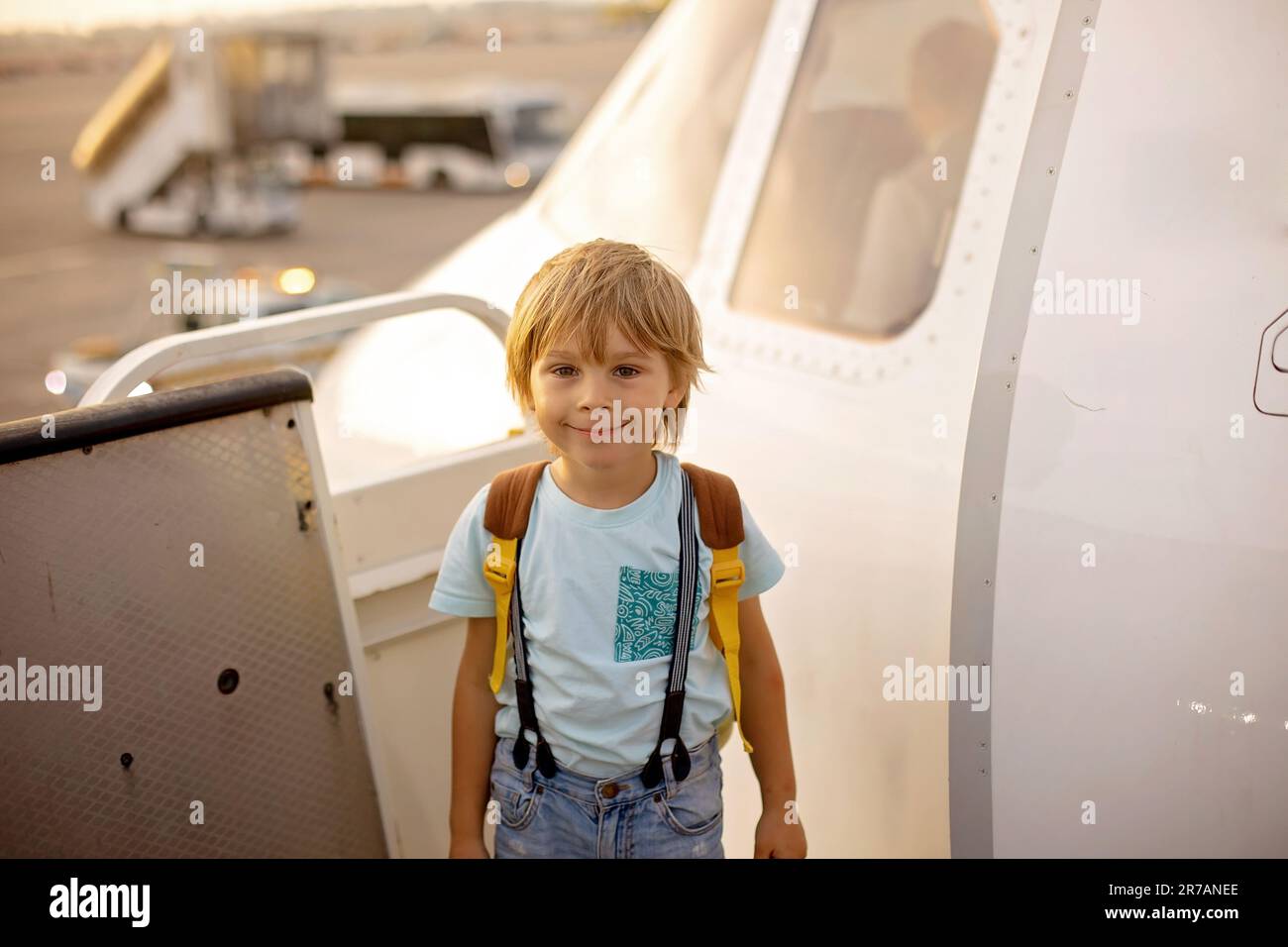 Cute blond child, kid with backpack, boarding airplane at the airport ...