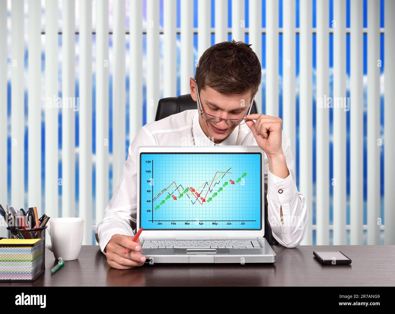 young trader sitting in office and looking on screen laptop with stock ...