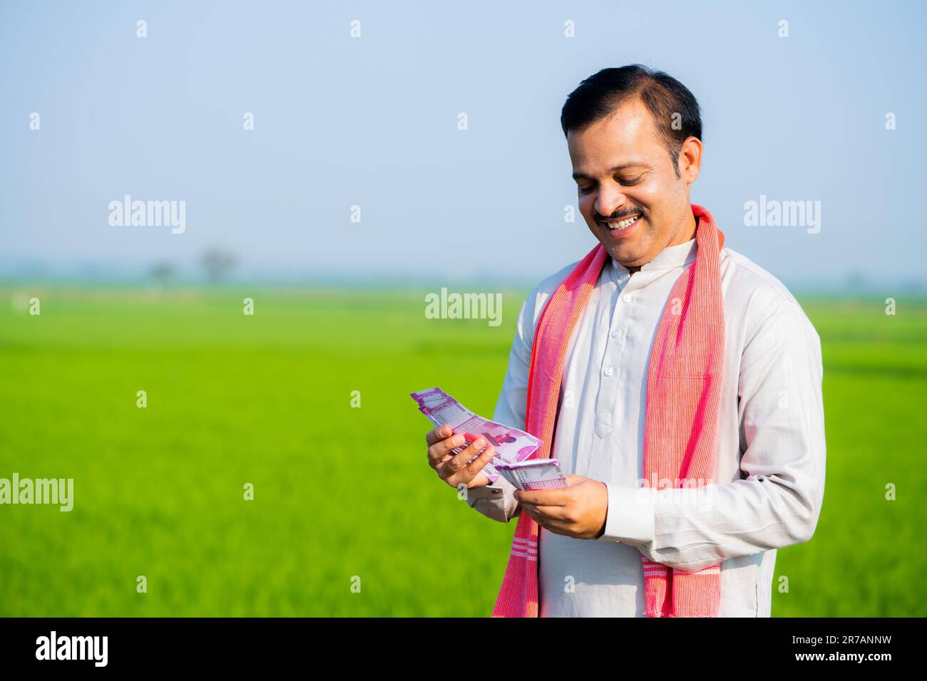 Happy indian village farmer counting money or currency at farmland with ...