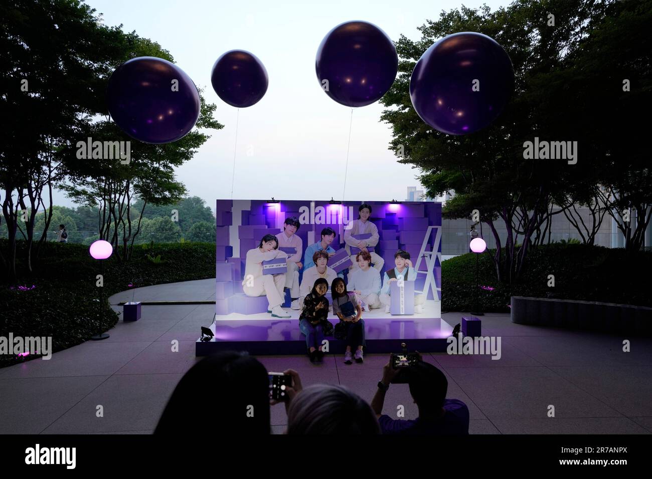 Fans of BTS pose for a souvenir photo in front of the banner showing K ...