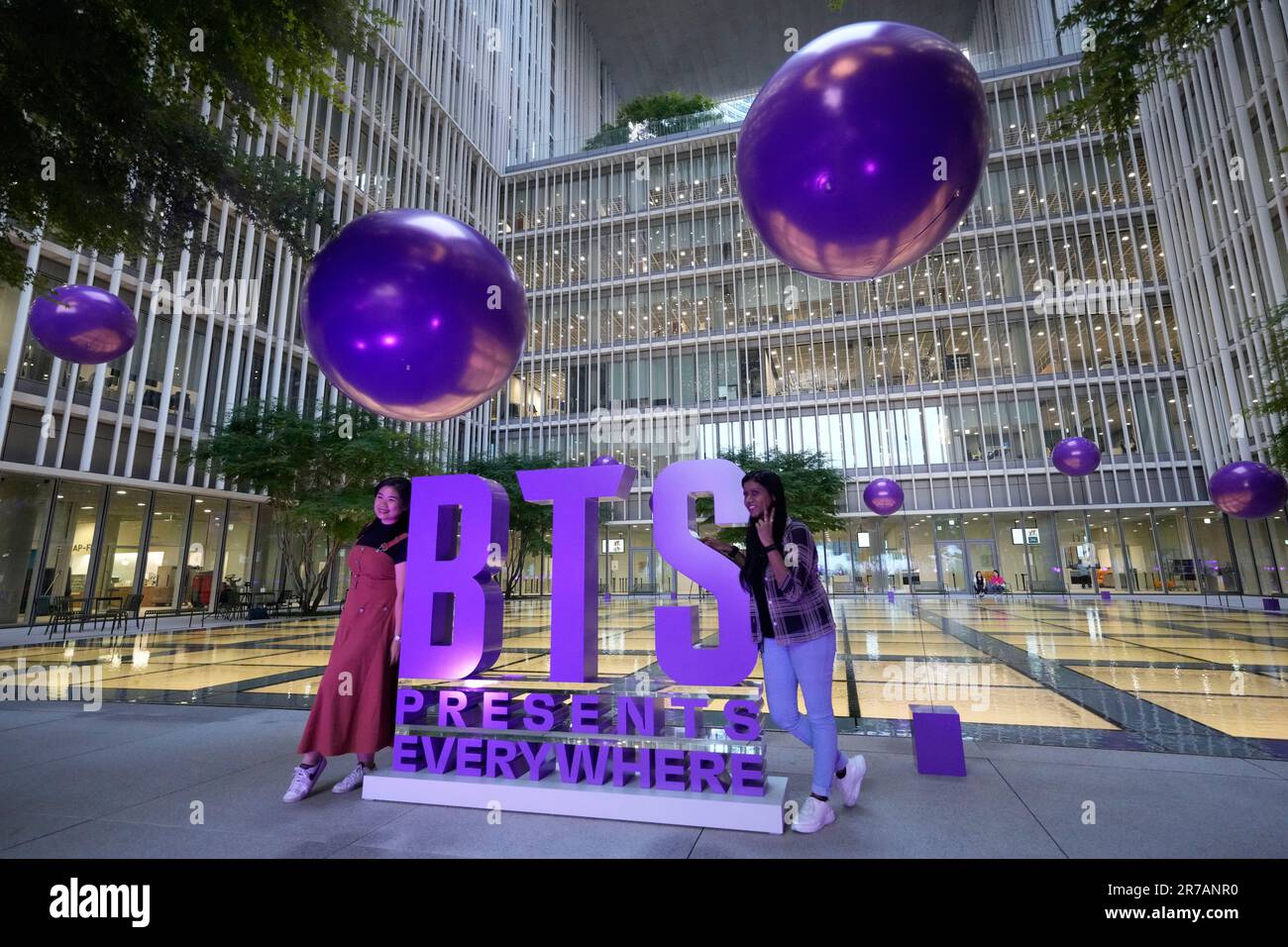 Fans of BTS pose for a souvenir photo with a logo of the K-pop band BTS ...