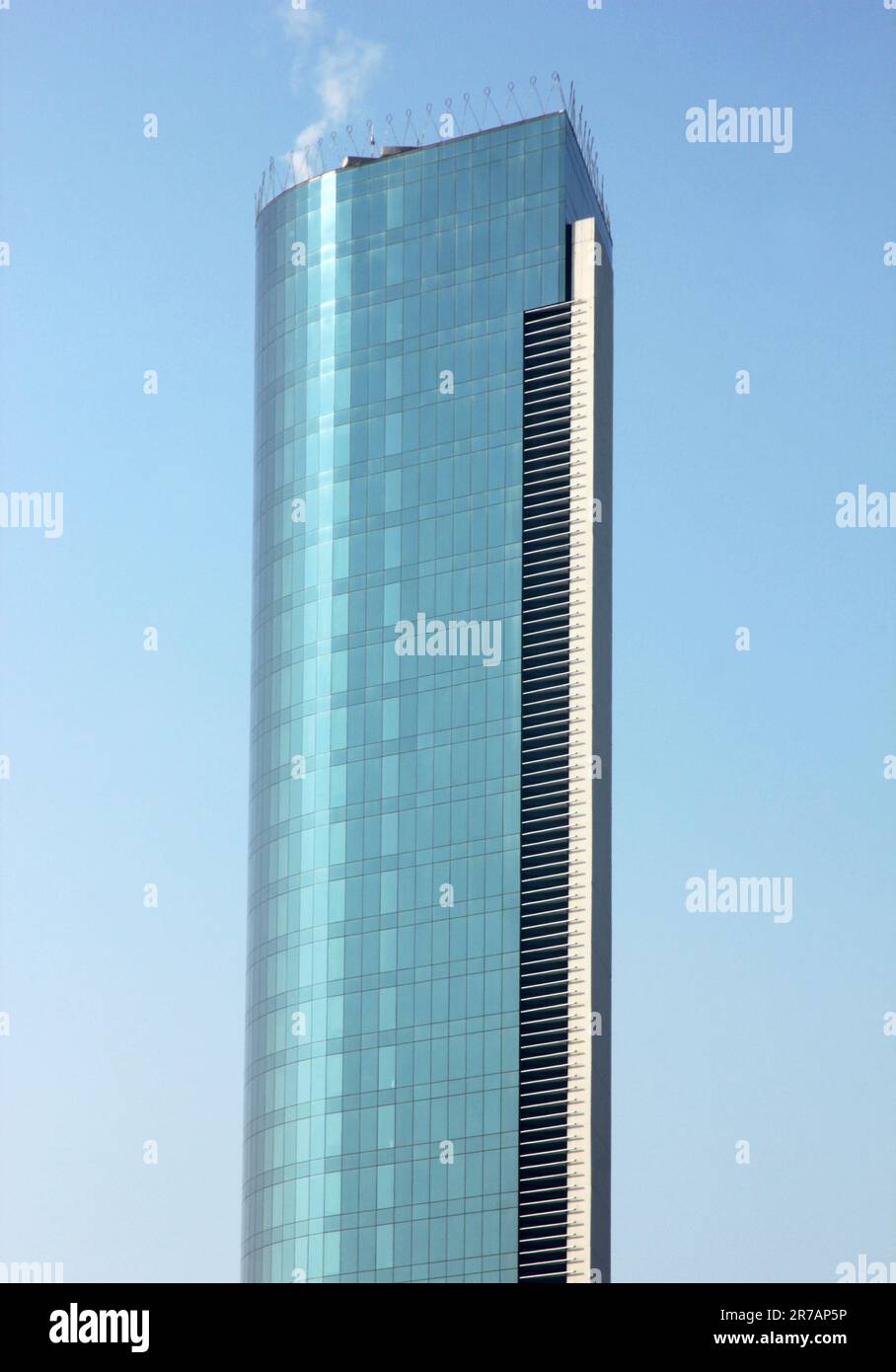 High-rise building with blue glass facade against the blue sky. Multi ...