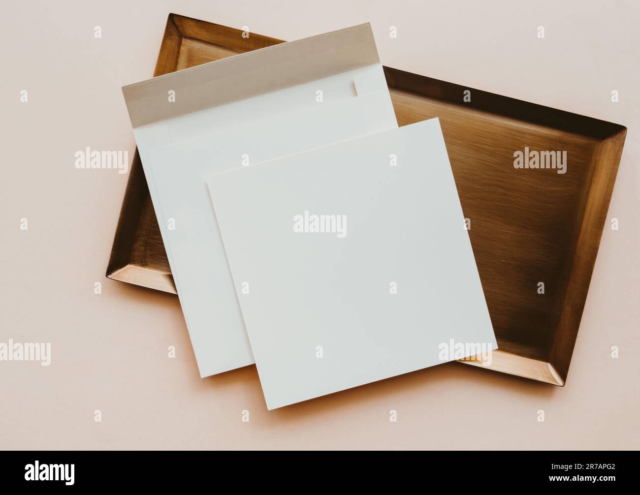 White blank paper square card mockup and envelope on gold tray on beige ...